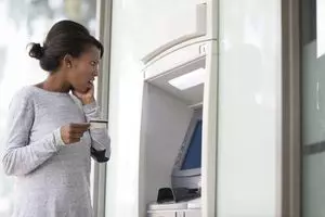 Một người phụ nữ trẻ với nét mặt bị sốc khi nhìn vào máy ATM